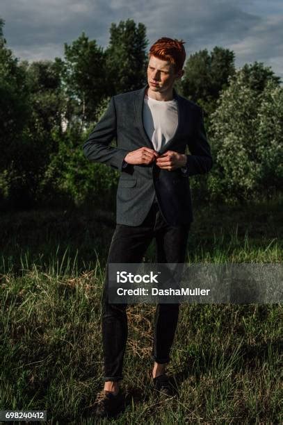 빨간 머리와 주 근 깨 자 켓을 입고 푸른 잔디에 서 매력적인 세련 된 젊은 남자 모델의 초상화 유행 야외 샷입니다 귀여운에