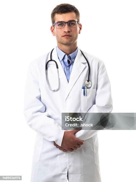 흰 코트를 입은 영웅의 초상화 하얀 배경에 서 있는 의료 병원에서 청진기를 들고 쾌활하게 웃고 있는 젊은 의사 코로나 바이러스
