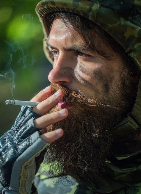 Soldier Man With Dirty Tired Face In Military Camouflage And Helmet Holding Cigarette And Soldier Man With Dirty Tired Face In Military Camouflage And Helmet Holding Cigarette And