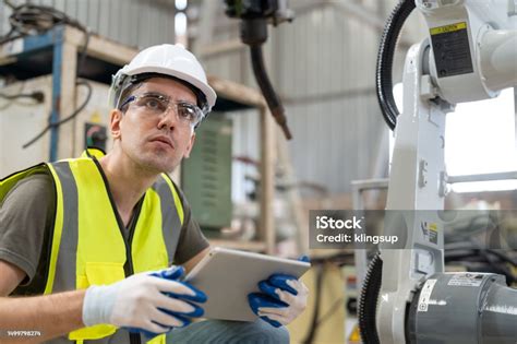 남성 자동화 엔지니어는 산업 공장에서 태블릿 검사 및 검사 제어 로봇 팔 용접기를 사용하여 헬멧 안전이 있는 조끼를 착용합니다 인공 지능 개념입니다 Stem 주제에 대한