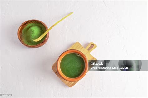 세라믹 컵에 갓 만든 말차 녹차와 대나무 계량 숟가락이 있는 나무 그릇에 담긴 말차 가루의 평면도 흰색 배경입니다 0명에 대한