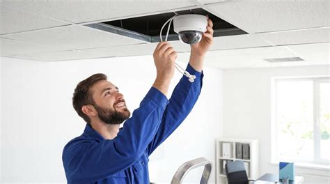 Technician Installing Security Camera In Suspended Ceiling 76678216
