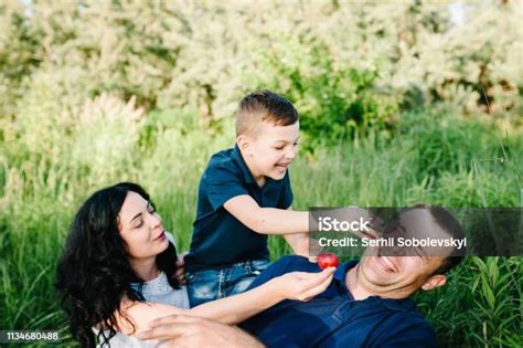 야외에서 함께 딸기를 먹는 휴가에 행복 한 젊은 가족 아버지 어머니 어린 소년이 담요 잔디 자연에 피크닉 엄마의 초상화 아빠 아들 가족 휴가의 개념입니다 가족에 대한 스톡