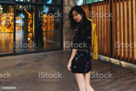 젊은 아시아 여자는 쇼핑 센터에 그녀의 방법에는 카메라 다시 보고 하는 미니 드레스를 입고 아름 다운 관광 여성 일본에서 입력의 옆에 서 있는 긴 검은 머리와 박물관 갈색