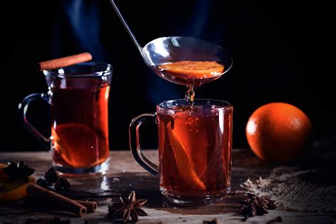 어두운 배경 소박한 나무 테이블에 계 피 스타 아니 스 정 향 오렌지 조각 같은 크리스마스 향신료와 유리 찻잔에 부 어 뜨거운 김이 Mulled 와인 멀드 와인에 대한 스톡