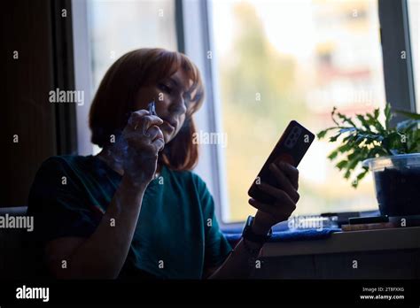 Redhead Woman Smoking With Attitude Takes Center Stage In This Photo Against A Window Stock