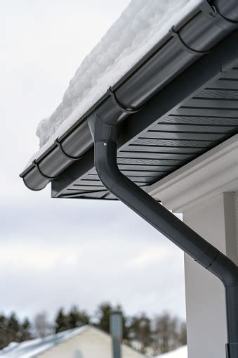 금속 다운 파이프 시스템 거터링 시스템 눈 아래 외부 하강 파이프 및 배수 파이프 회색 금속 타일로 만든 지붕과 겨울에 눈의