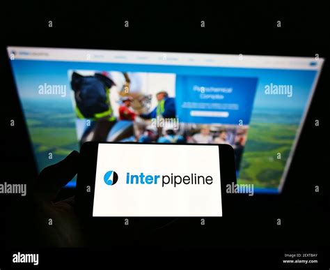 Person Holding Mobile Phone With Logo Of Canadian Oil Infrastructure Company Inter Pipeline On