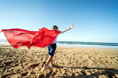 슈퍼히어로 아이는 모래사장 일몰 해변에서 빨간 마스크와 망토를 입고 달리며 즐거운 시간을 보내고 있다 여름 방학 개념 사람들에 대한 스톡 사진 및 기타 이미지 Istock