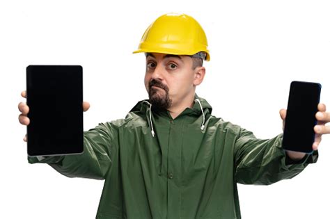 흰색 배경에 디지털 태블릿과 스마트 폰을 보여주는 젊은 엔지니어 녹색 비옷과 하드 햇 Brand Name Online