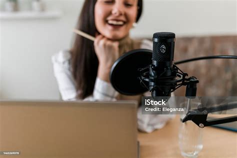 팟캐스트를 녹음하고 녹음 스튜디오에서 마이크와 헤드폰을 사용하여 라이브 스트리밍을 하는 젊은 웃는 여성의 입에 선택적으로 집중 Radio Show에 대한 스톡 사진 및 기타