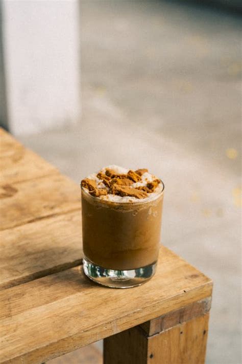 나무 테이블 위에 비스킷 토핑이 있는 아이스 커피 · 무료 스톡 사진