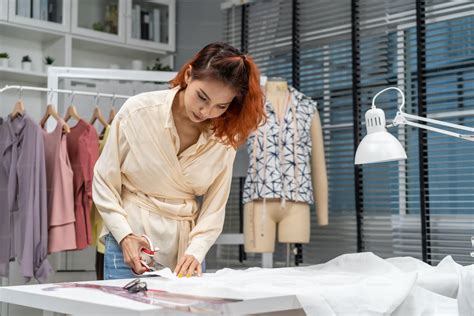양복 아틀리에에서 새 옷을 만들기 위해 일하는 아시아 양복 여성 매력적인 어린 소녀 패션 디자이너 양장점 사용 가위 절단 직물