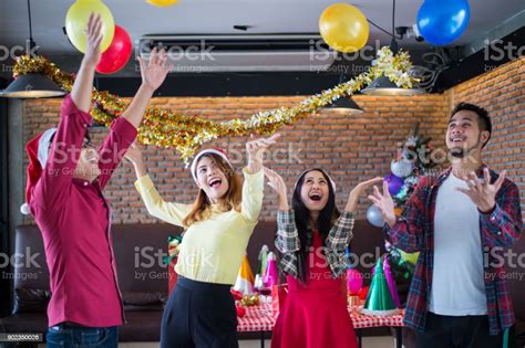 아시아 남자와 여 자가 크리스마스 파티에서 재미 춤 및 레스토랑 개념의 크리스마스 파티 또는 새 해 파티에서 풍선 게임 산타 클로스 모자를 착용 가족에 대한 스톡 사진 및