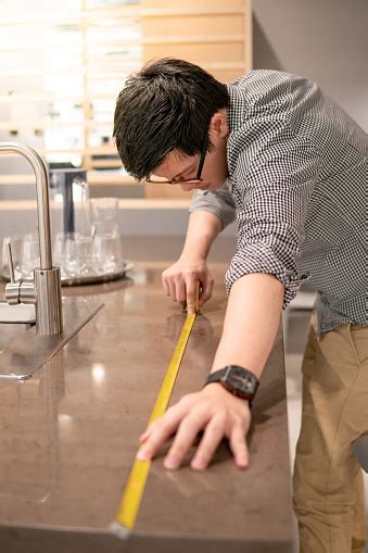 젊은 아시아 남자 쇼 룸에서 현대 부엌 카운터에 화강암 싱크대를 측정 하기 위한 측정 테이프를 사용 하 여 홈 개선 위한 가구 쇼핑 인테리어 디자인 컨셉 가구에 대한 스톡