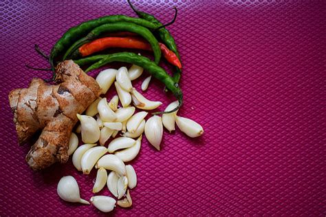 껍질을 벗긴 마늘의 스톡 사진 보라색 쵸핑 보드에 보관 된 녹색 칠리와 생강이 거의 없습니다 인도 카르나타카 방갈로르에서 자연광