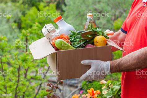검역 중 의 배달 O 식품 기부 개념 채소 과일 및 기타 음식이 들어있는 의료 장갑에 골판지 상자를 들고있는 남자 코로나바이러스