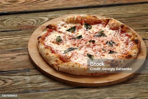 어두운 질감의 배경에 나무 보드에 신선한 바질 잎과 함께 제공되는 컷되지 않은 이탈리아 피자 토마토와 페스토 소스를 곁들인