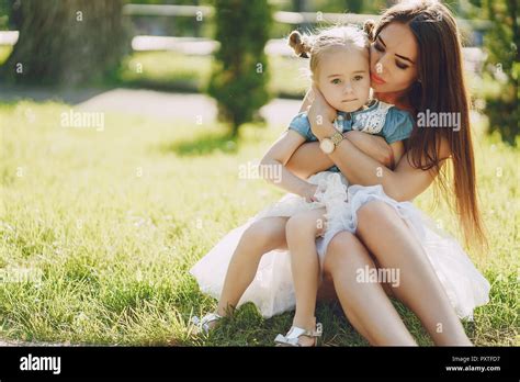 Une jeune et belle à poil long et mince maman marche dans le parc avec sa petite fille Photo