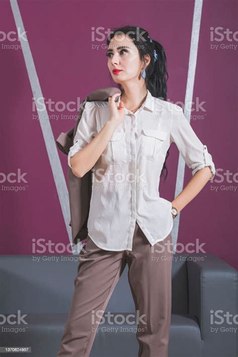 흰색 셔츠를 입은 아름다운 사업가가 분홍색 벽에 맞서 사무실에 서 있습니다 카메라를 멀리 쳐다본다 35 39세에 대한 스톡 사진 및 기타 이미지 Istock