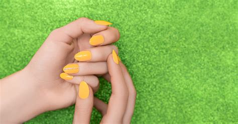 노란 네일 디자인의 여성 손 노란색 매니큐어 매니큐어 여자는 녹색 반짝이 배경에 손을 공간을 복사합니다 네일 살롱에 대한 스톡 사진 및 기타 이미지 Istock