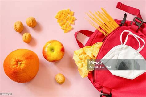 다양한 파스타 과일 견과류가 있는 빨간 배낭 분홍색 배경에 보호 마스크 음식 배달 개념 쇼핑 관광 음식 감귤류 과일에 대한 스톡