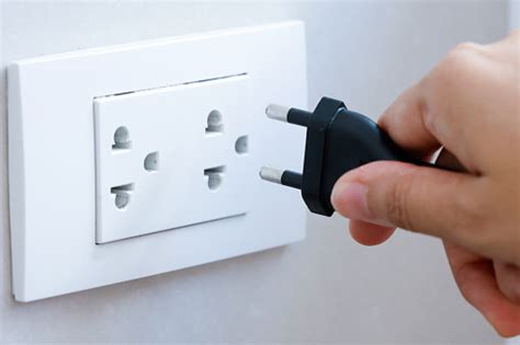 손 잡고 있는 플러그는 벽 전원 콘센트 소켓 절전 개념 에너지 절약 에너지 절약의 전기 콘센트에 전원 플러그에 연결합니다