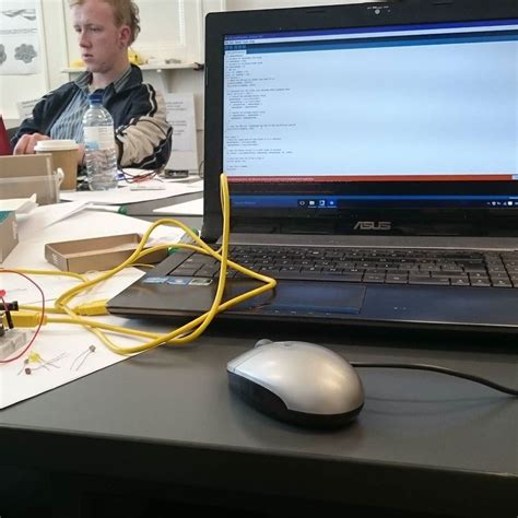 a laptop computer sitting on top of a desk next to a mouse and wires in