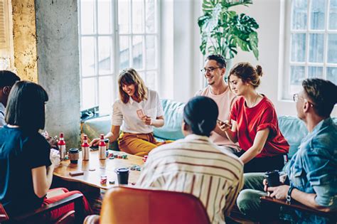 현대 아파트에서 알코올 음료와 포커 칩과 테이블에 앉아 보드 게임에서 재생 캐주얼 착용 다문화 사람들의 그룹 휴식을위한 친절한 회의를 즐기는 다양한 힙스터 20 24세에