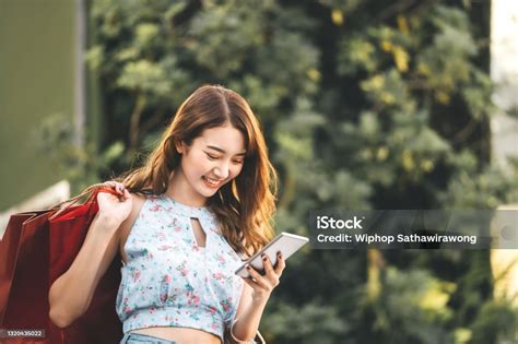 젊은 성인 아시아 여자 온라인 응용 프로그램에 대 한 휴대 전화를 사용 하 고 쇼핑 백을 들고 아시아에 대한 스톡 사진 및 기타 이미지 Istock