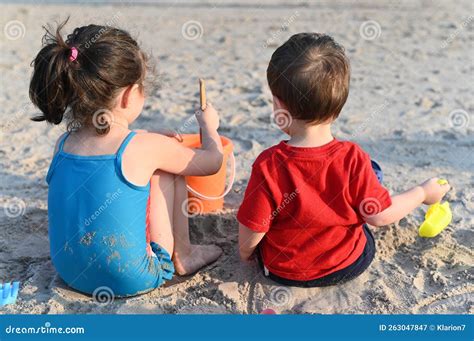 Brother And Sister In Bathing Suits Playing With Beach Toys In The Sand