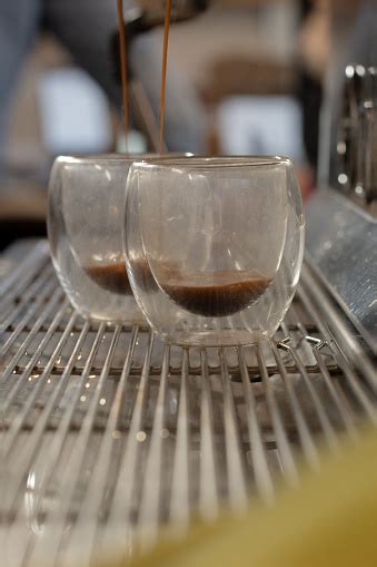 초점이 맞지 않는 배경의 얇은 커피 실로 채워진 에스프레소 머신에서 두 개의 에스프레소 샷 잔을 클로즈업 0명에 대한 스톡 사진