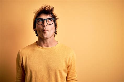 캐주얼 한 티셔츠와 안경을 입고 고립 된 노란색 배경 위에 입술 미친 코믹 한 제스처로 물고기 얼굴을 만드는 젊은 잘생긴 남자 재미있는 표현 T 셔츠에 대한 스톡 사진 및