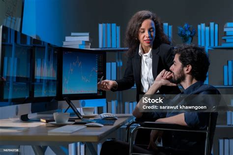 열심히 일하는 비즈니스 남녀 설정된 목표에 따라 작업을 완료하기 위해 밤늦게까지 일하기 두 사람은 회사의 재무 그래프를주의 깊게 살펴 보았습니다 2명에 대한 스톡 사진 및