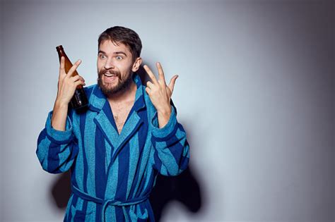 병에 알코올 음료를 마시고 밝은 배경에 파란색 가운을 입은 남자가 잘린 모습 가득 찬에 대한 스톡 사진 및 기타 이미지 가득