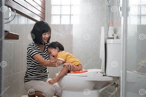 Mutterhilfe Ihre Tochter Auf Dem Der Toilette Sitzen Pinkeln Stockbild