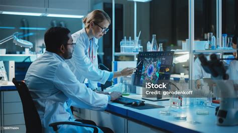 바이러스 분석 소프트웨어 사용자 인터페이스를 보여주는 화면이있는 개인용 컴퓨터에서 작업하는 생물 공학자를 가진 여성 연구 과학자