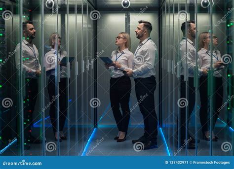 Workers In A Data Center Walking Between Rows Of Server Racks Royalty Free Stock Image