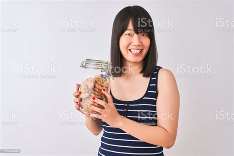 행복한 얼굴 서서 치아를 보여주는 자신감 미소와 함께 미소와 고립 된 흰색 배경 위에 쿠키의 항아리를 들고 젊은 아름다운 중국 여자 긍정적인 감정 표현에 대한 스톡 사진 및