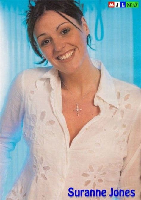 A Woman In White Shirt Smiling At The Camera With Her Hands On Her Hips And Wearing A Cross Necklace