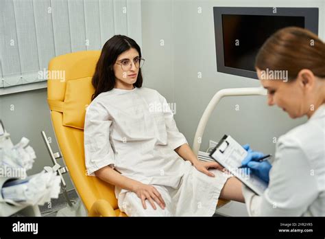 A Gynecologist Helps A Female Patient During A Health Exam In A Modern Medical Office Stock