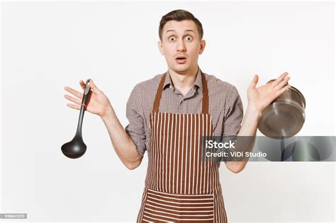 남자 요리사에 줄무늬 갈색 앞치마 지주 실버 스테인레스 광택 알루미늄 빈 Stewpan 팬 또는 남 비 흰색 배경에 고립 된 국자 남자가 정부 또는 Houseworker