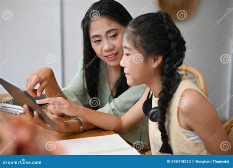 Mom Teaching Her Daughter`s Homework Using Digital Tablet Together