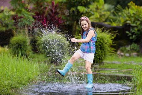 孩子们撑着伞在夏日的雨中玩耍。素材 花瓣网