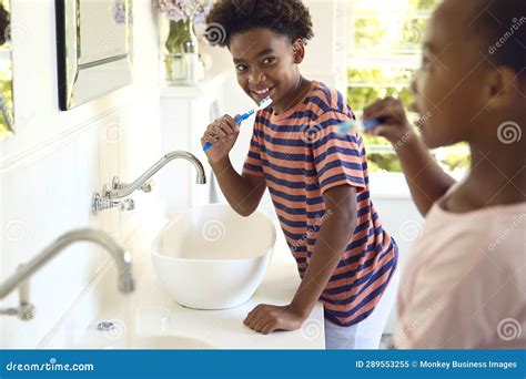 Brother And Sister In Bathroom At Home Brushing Teeth Together Stock