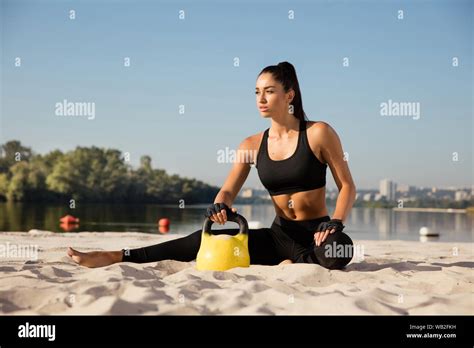 Young Healthy Woman Stretching With Weights At The Beach Single