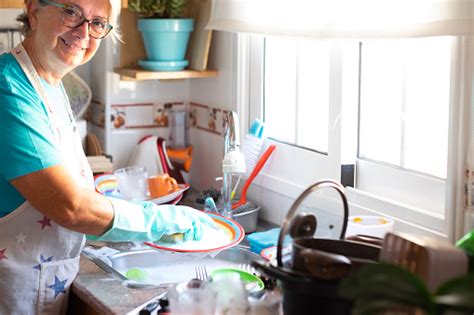 앞치마와 장갑을 착용한 미소 짓는 선배 여성의 회색 머리 부엌의 코너입니다 직장에서 할머니 창에서 밝은 빛 가사 집안일에 대한 스톡 사진 및 기타 이미지 Istock