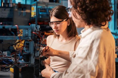 Free Photo Young Man And Woman In Protective Glasses Doing Experiments In Robotics In A