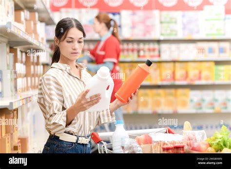 Customer Holding Two Bottles Of Detergent And Checking Labels She Is Comparing Products