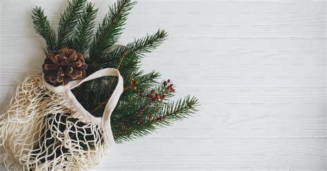 겨울 장식 제로 폐기물 휴일과 그물 쇼핑백 텍스트를 위한 공간이 있는 상위 보기입니다 흰색 소박한 배경에 녹색 가문비나무 가지와 솔방울이 있는 재사용 가능한 면 가방